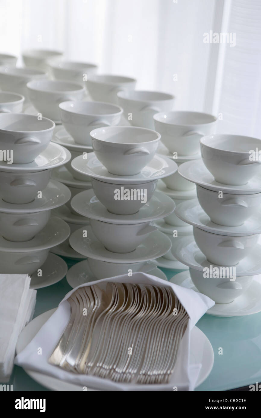 A large amount of spoons and stacked cups and saucers Stock Photo - Alamy