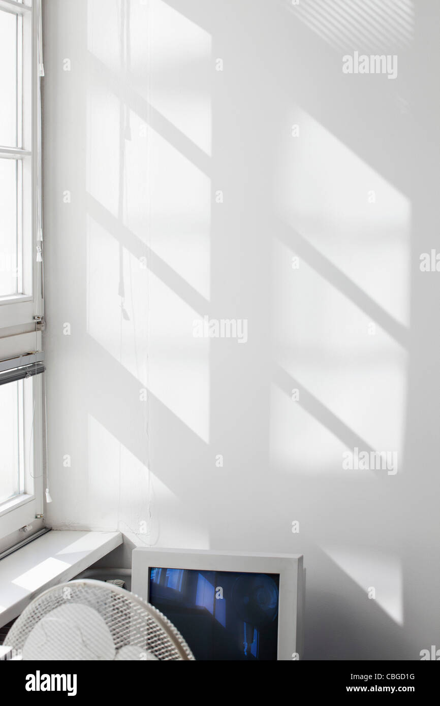 Outline of window shadowed on wall behind fan and monitor Stock Photo ...