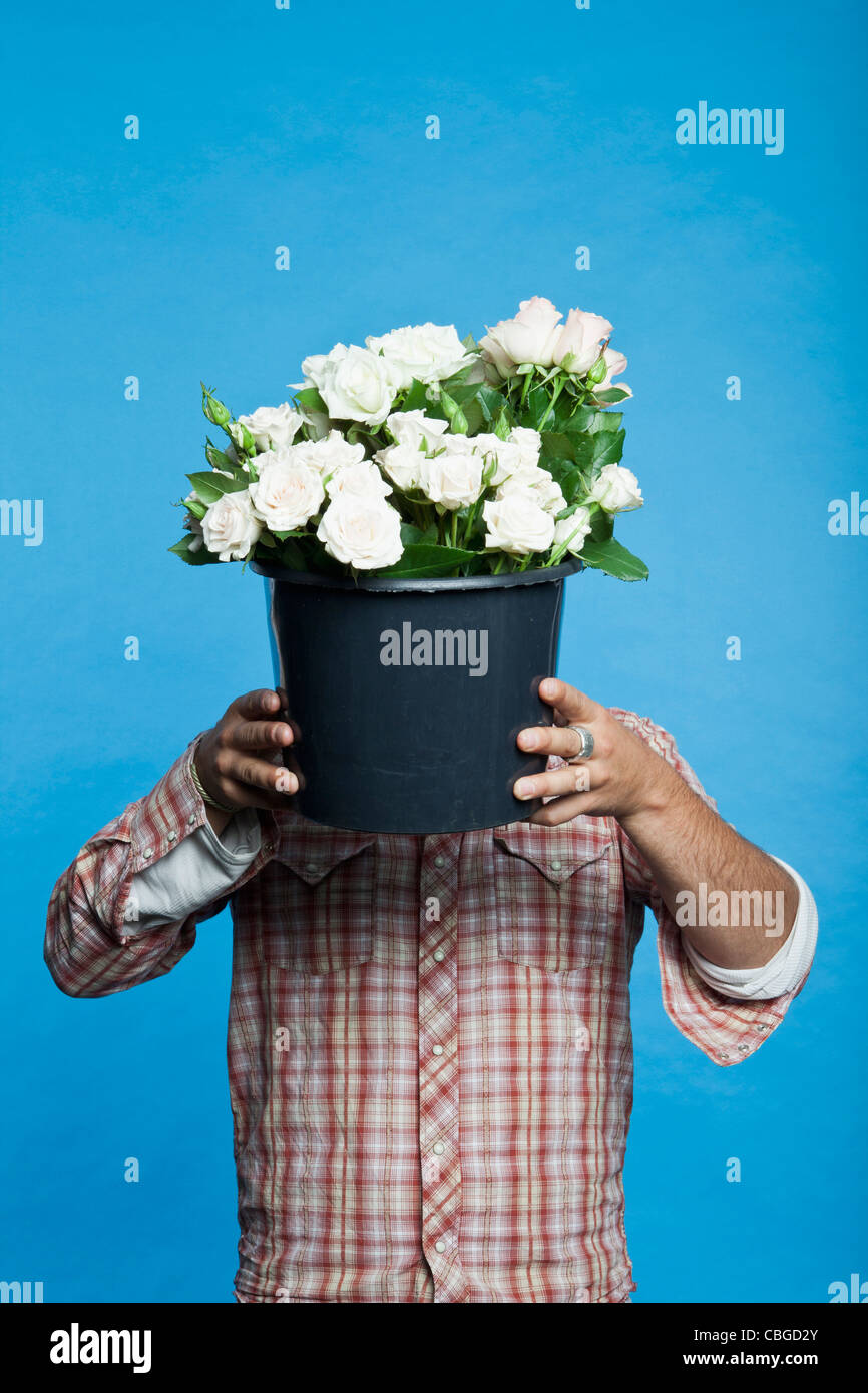 Man holding black bucket of flowers in front of his face Stock Photo ...