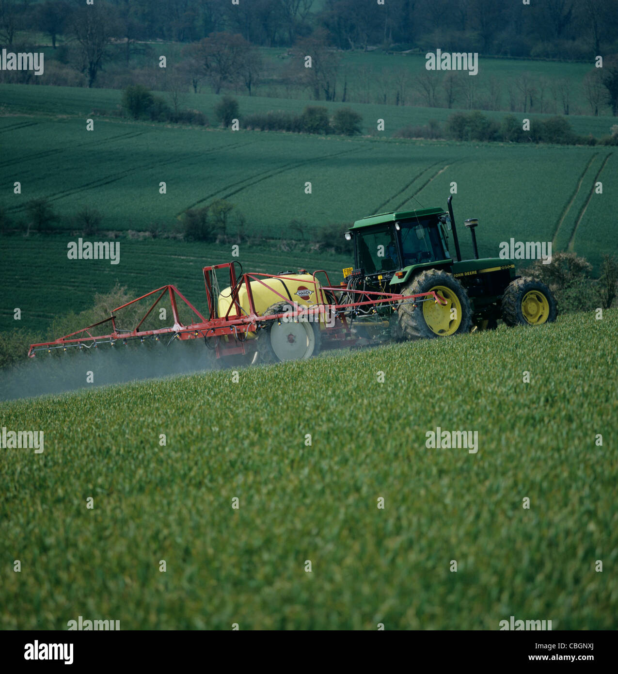 John Deere tractor & Hardi trailed sprayer spraying wheat crop in ...
