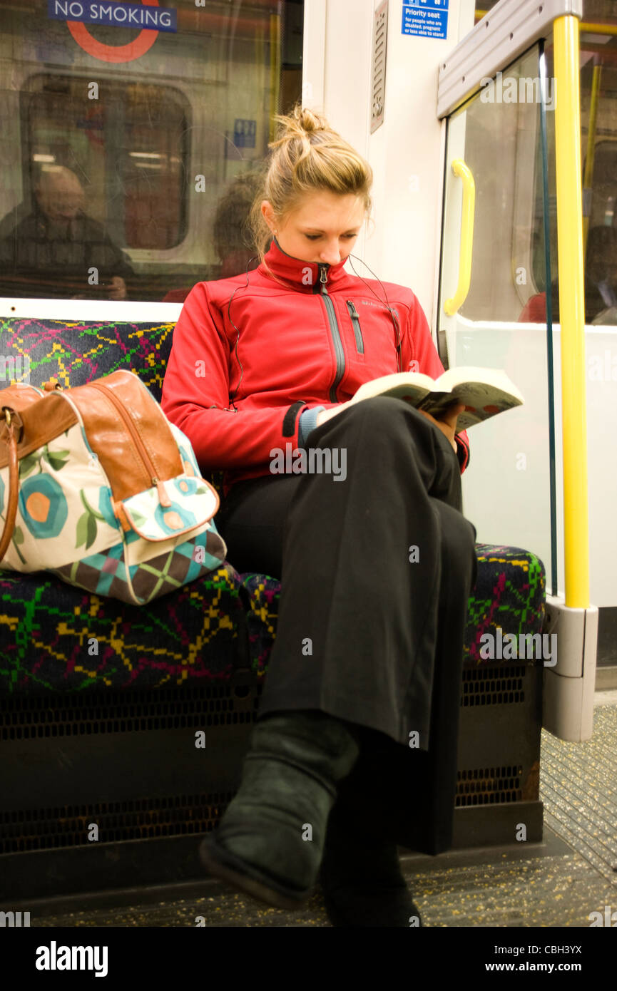 Lady on the underground. Reading a book Stock Photo - Alamy
