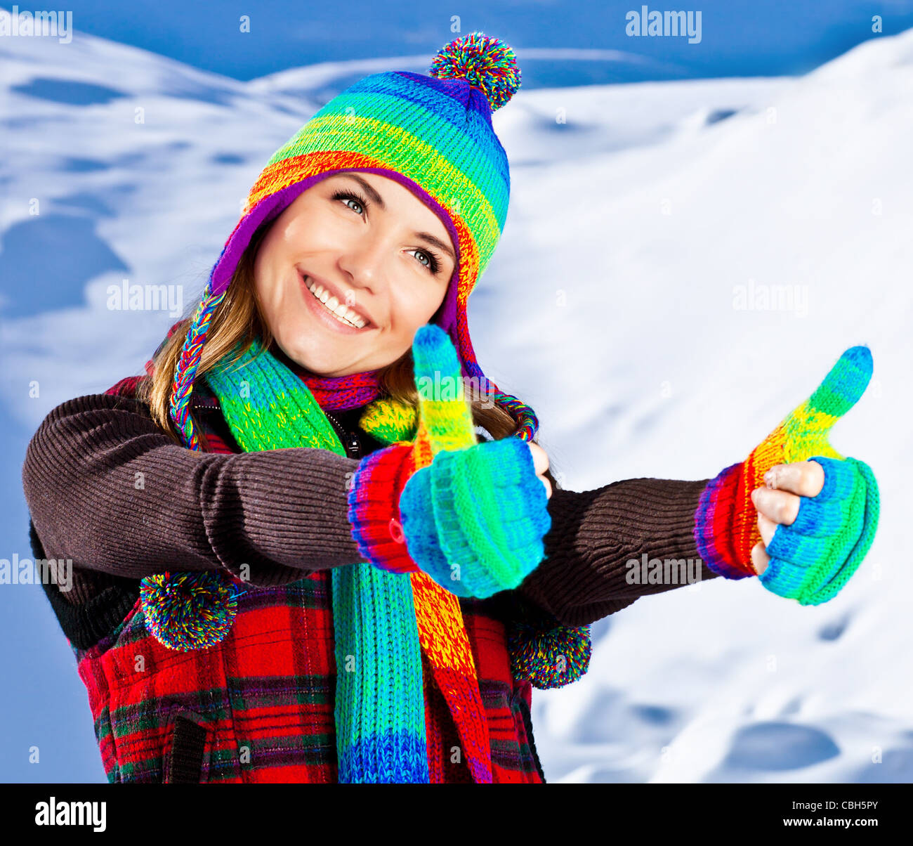Colorful thumbs up of a happy smiling girl wearing winter clothes ...