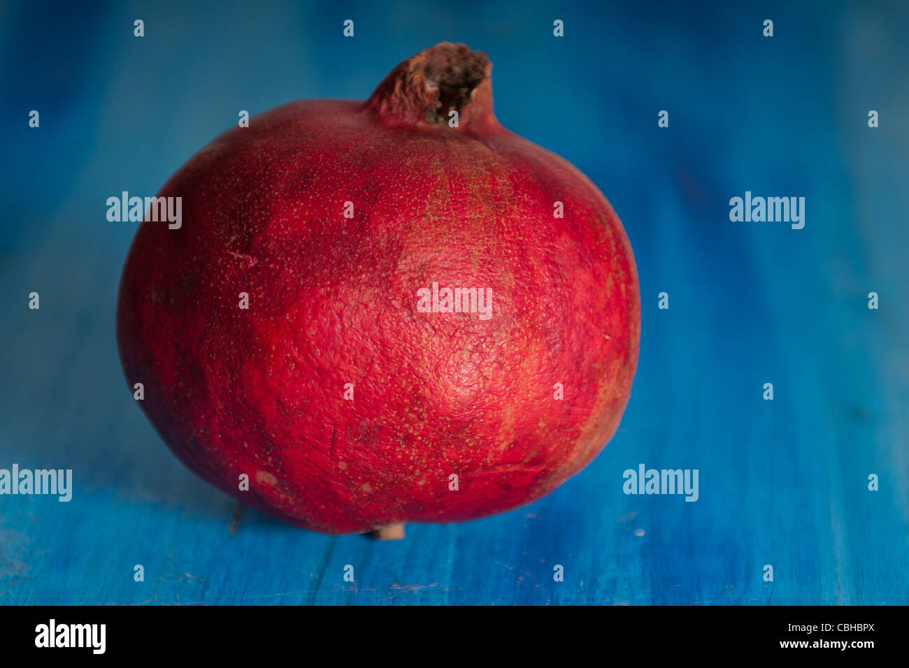 Whole ripe pomegranate on a blue background Stock Photo - Alamy