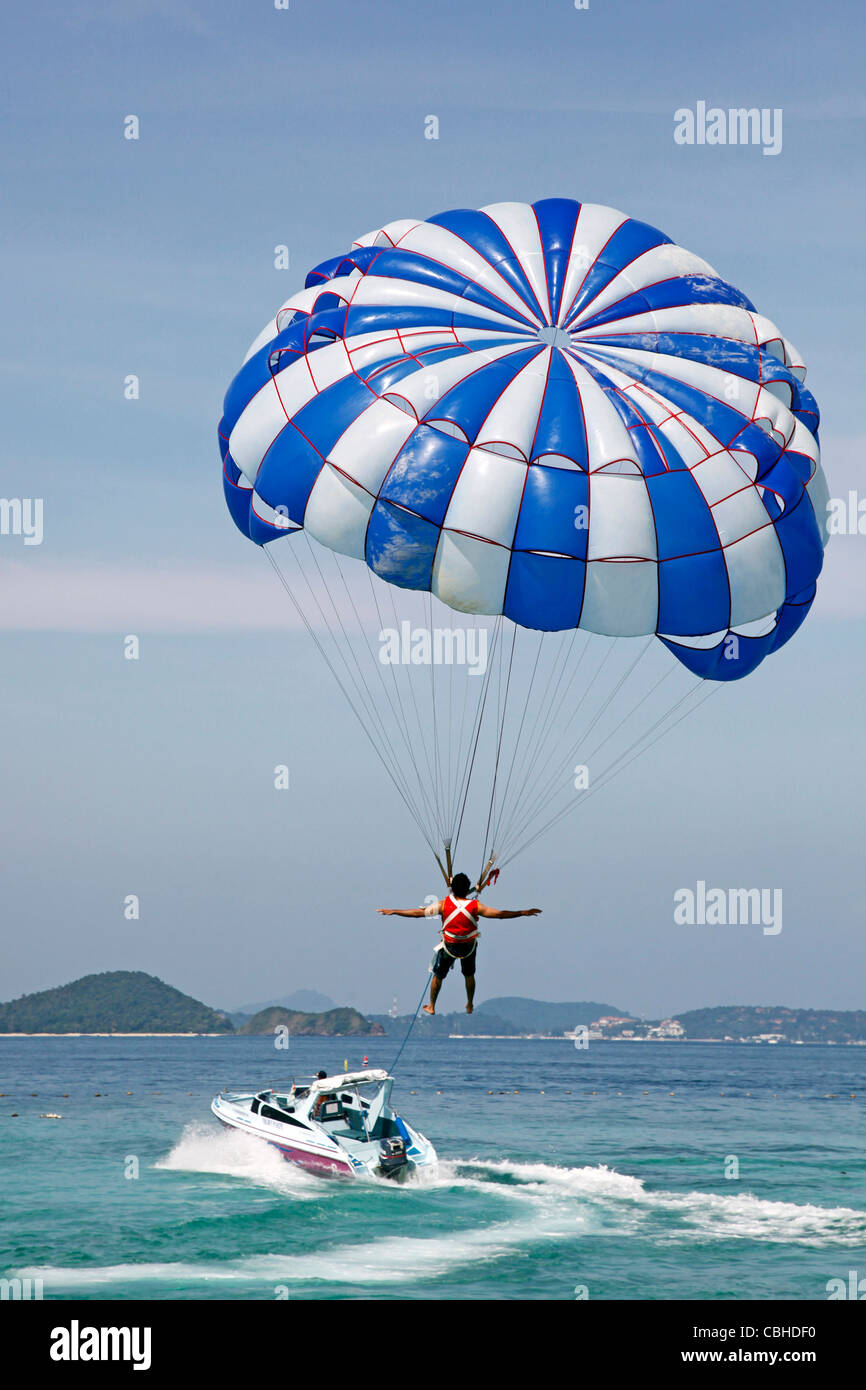 Tourists enjoying sport activities, parasailing with a speedboat and ...