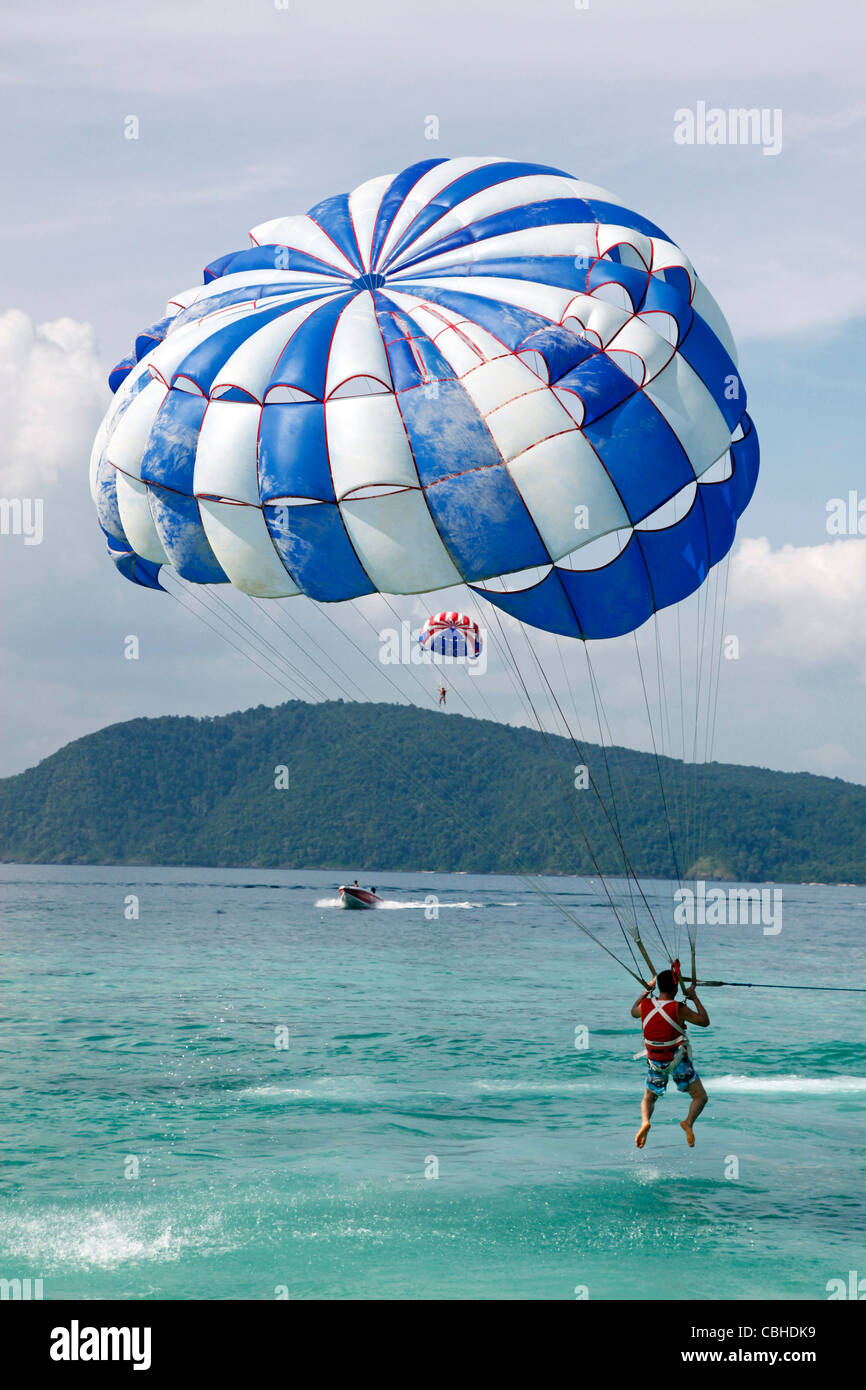 Tourists enjoying sport activities, parasailing with a speedboat and ...