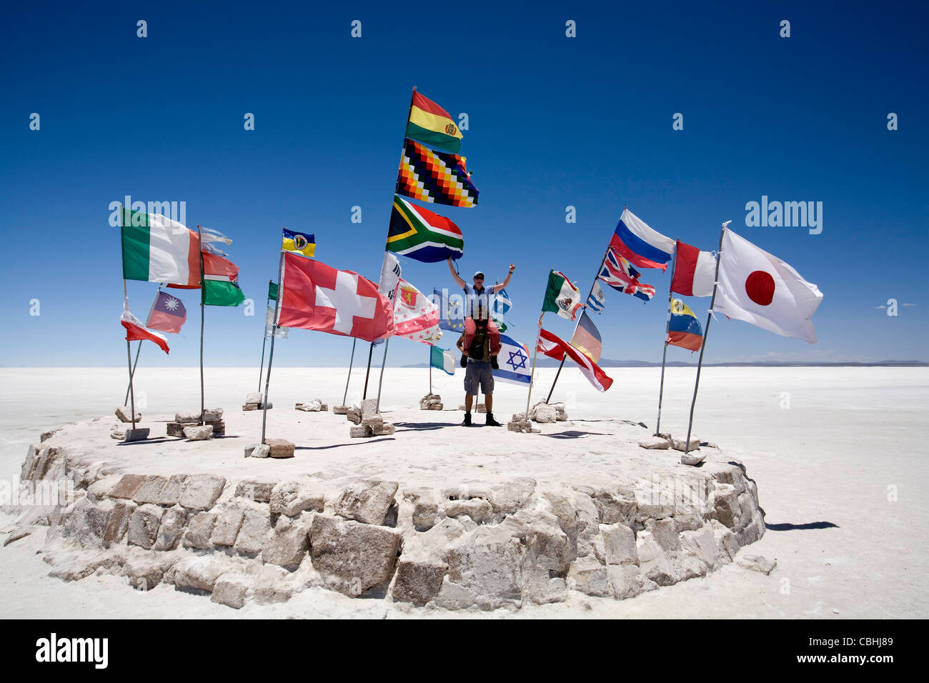 Joyful couple at the flags spot in Salar de Uyuni (salt flat), Bolivia ...