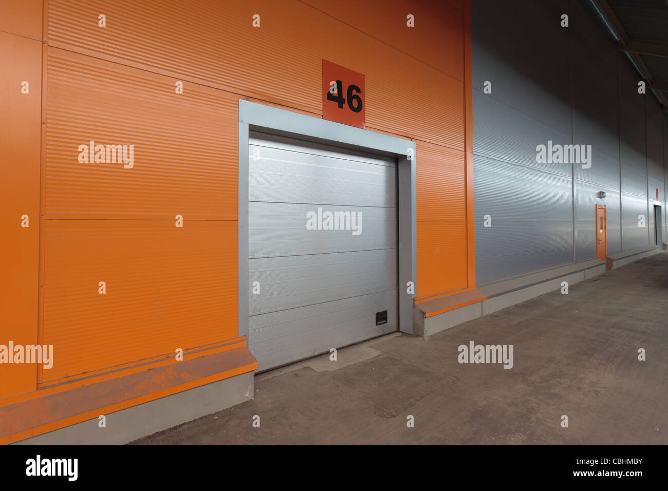 Modern warehouse's gate number 46 in orange wall Stock Photo - Alamy