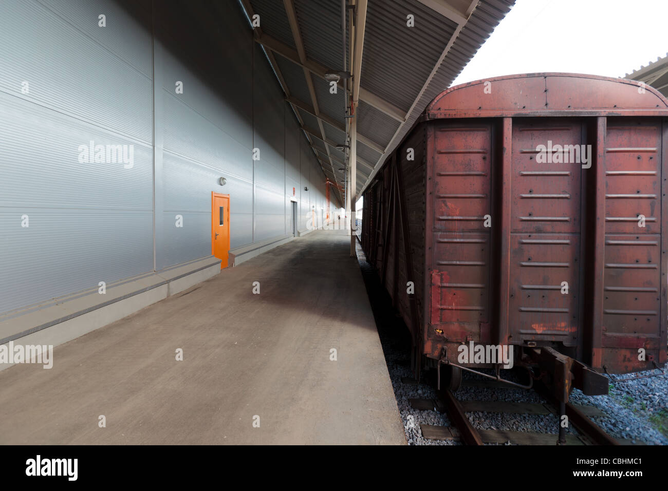 Old railway freight wagon standing at the platform of modern warehouse ...