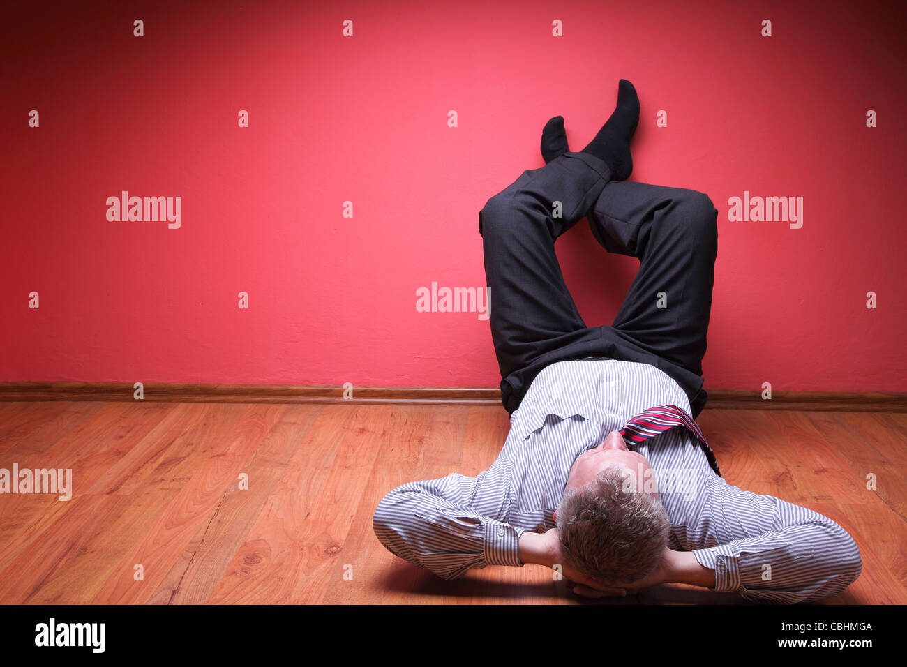 men lying in the floor on red wall background Stock Photo - Alamy