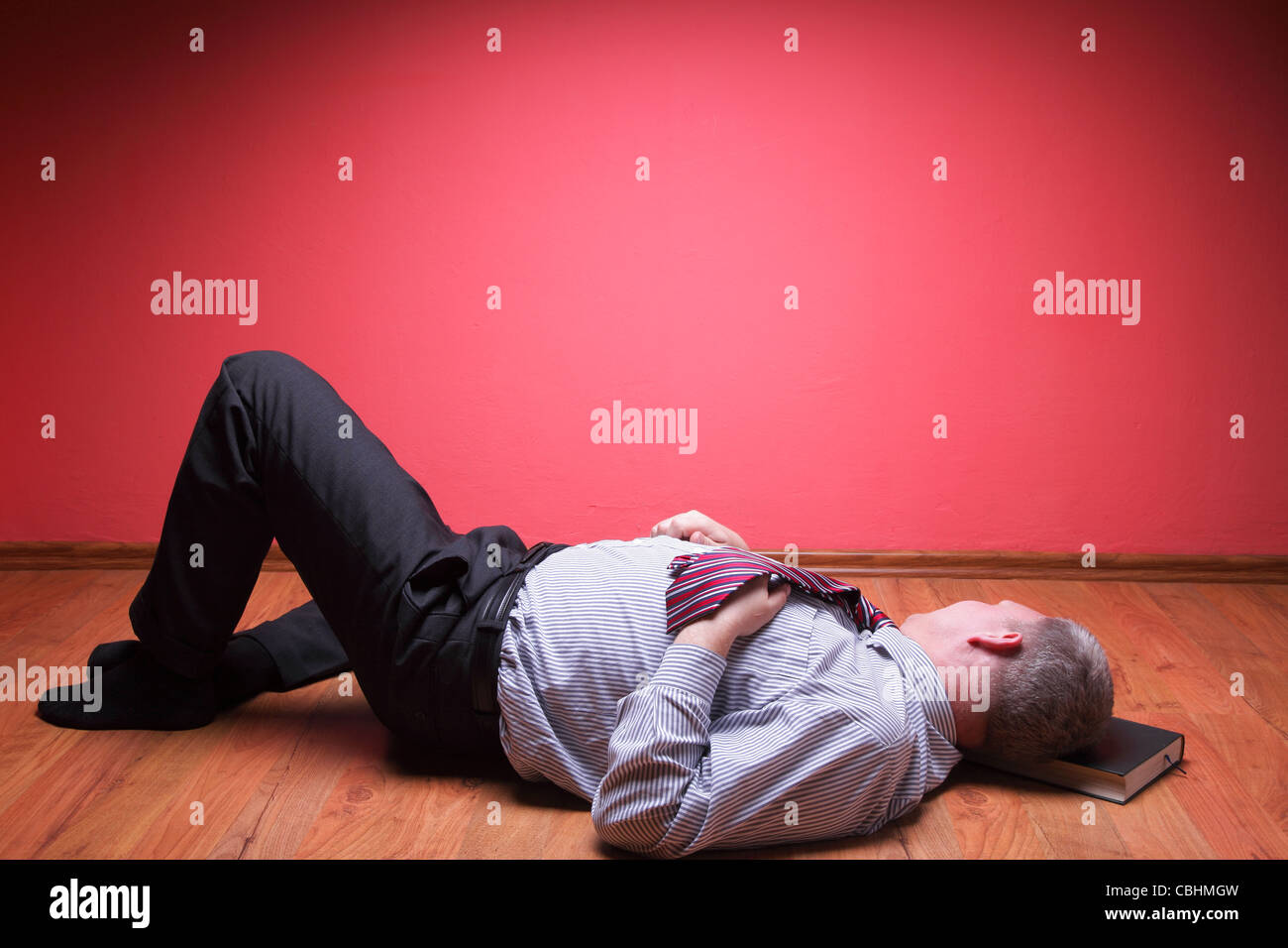 men lying in the floor on red wall background Stock Photo - Alamy