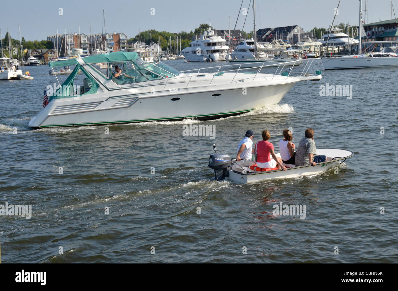People in a small boat ride near a large boat in the harbor in ...