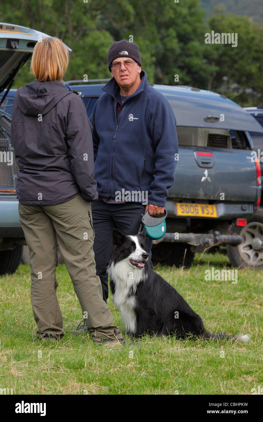 Man and woman chatting with sheep dog at their feet Stock Photo - Alamy