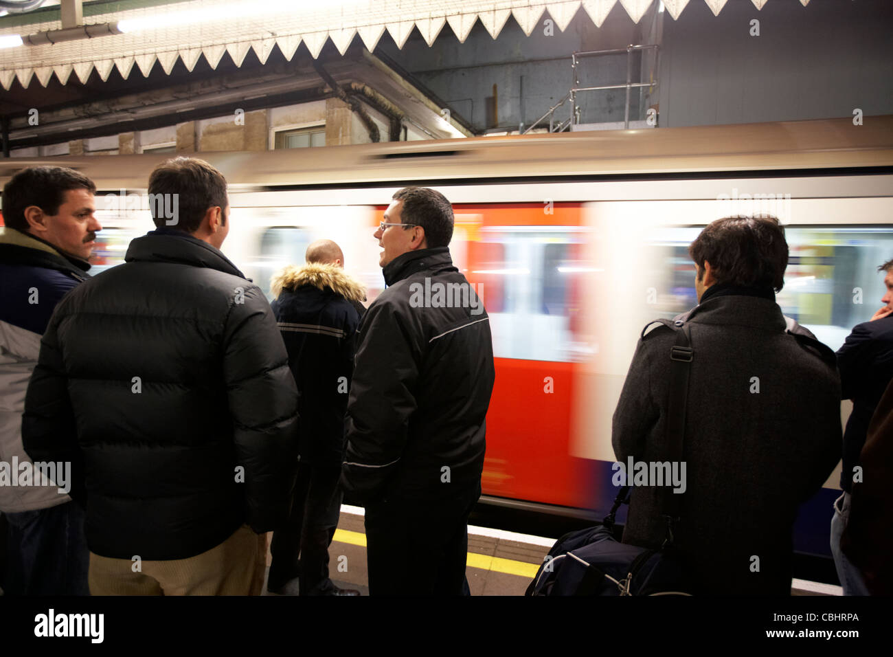 people standing on the platform as train speeds by london underground ...