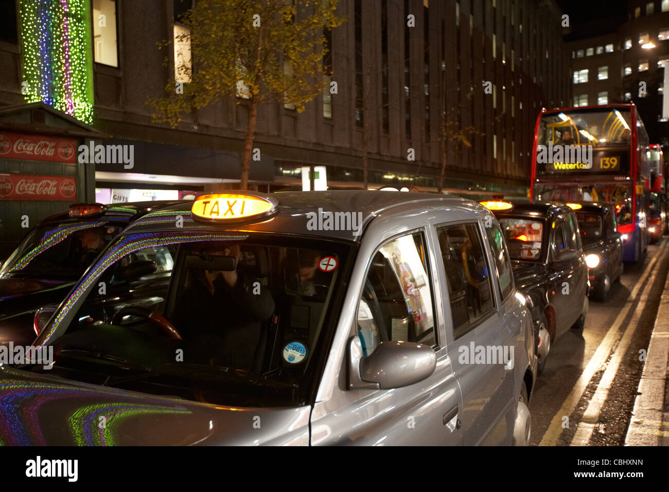 row of black london cabs taxis at night on shopping street in central ...