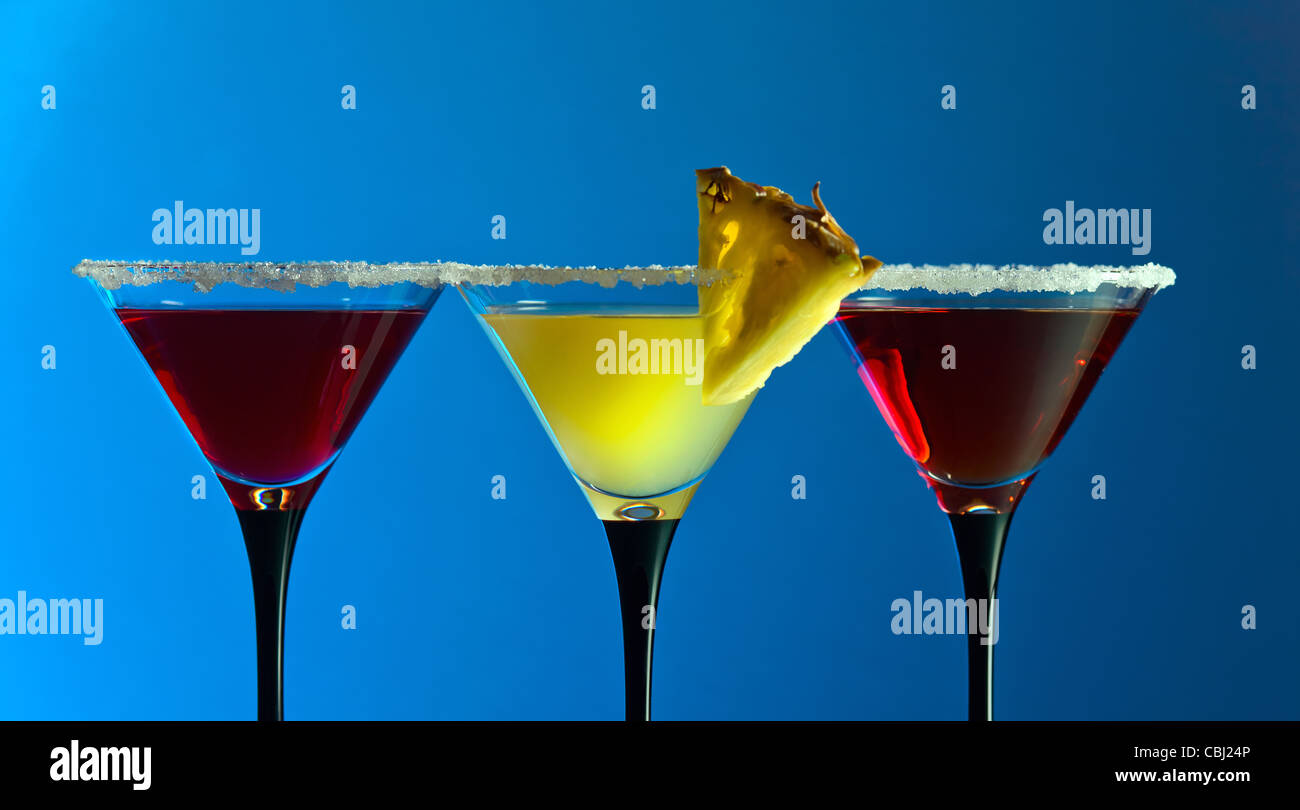Three glasses with a cocktail on a blue background Stock Photo - Alamy