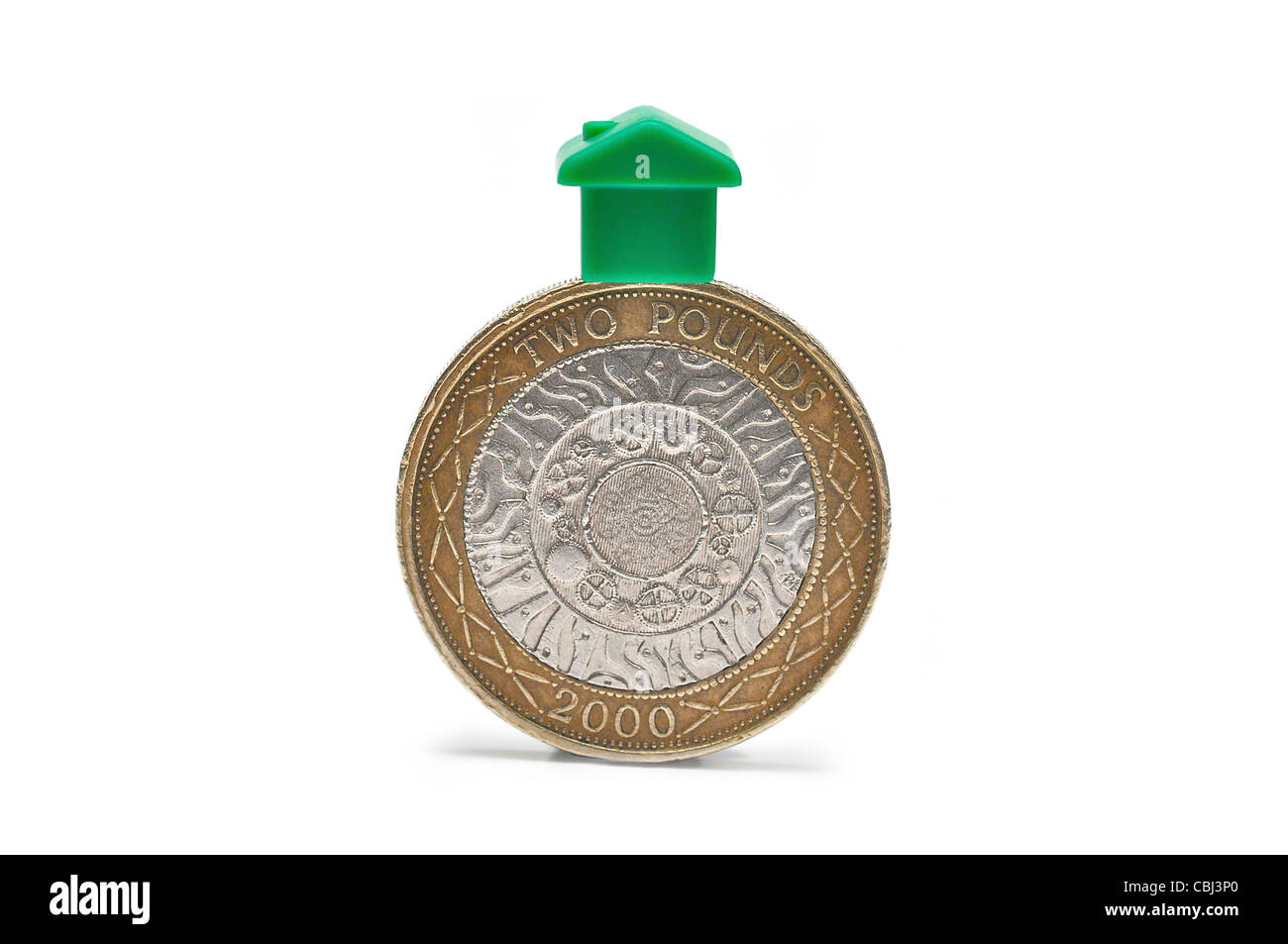 Two Pound coin with green house balanced on it Stock Photo - Alamy