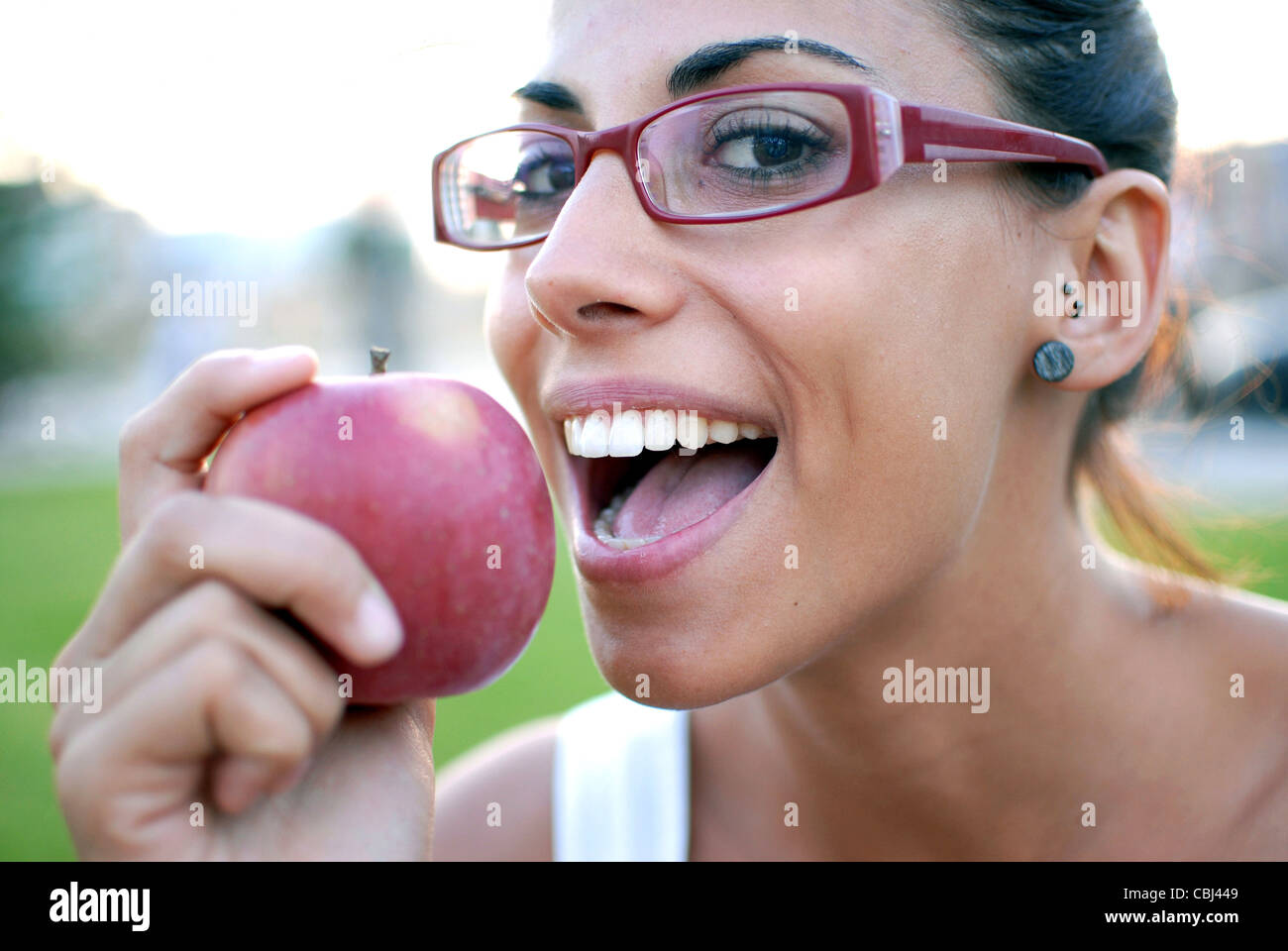 Young woman eating a red apple in nature Stock Photo - Alamy