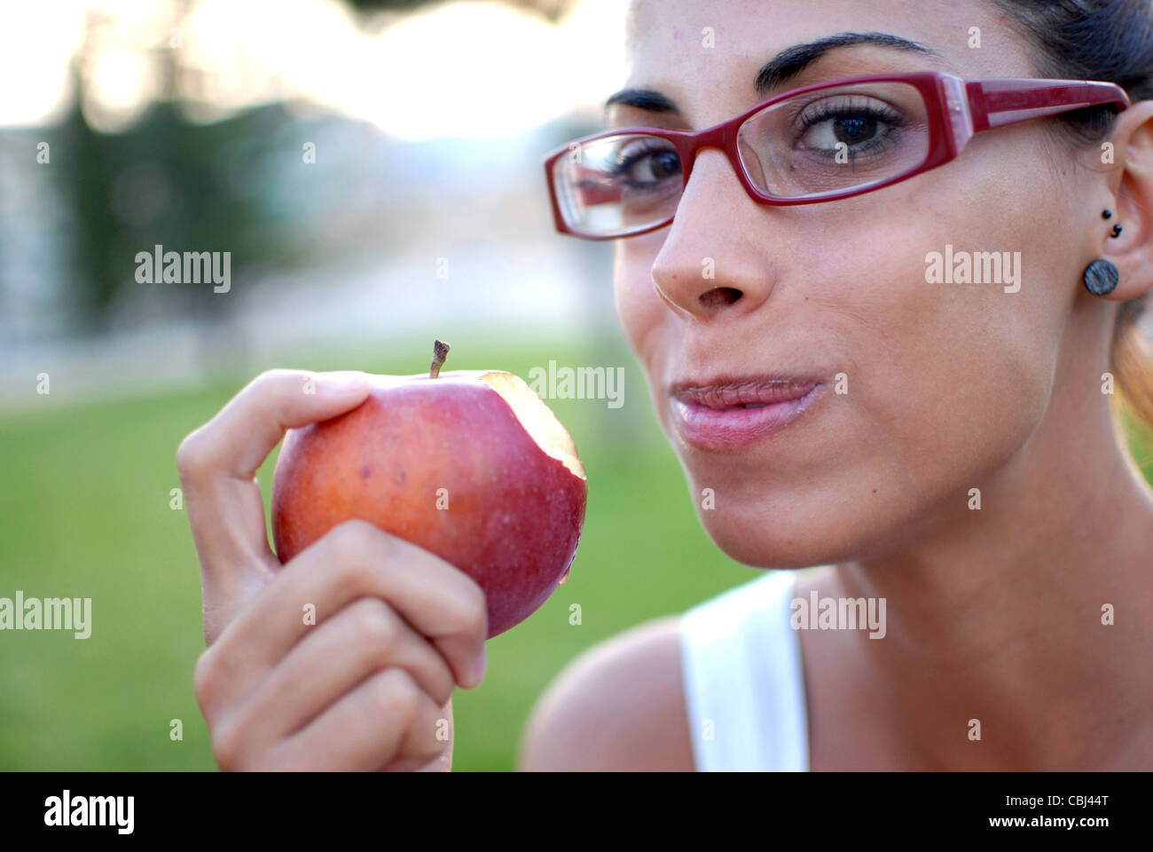 Young woman eating a red apple in nature Stock Photo - Alamy