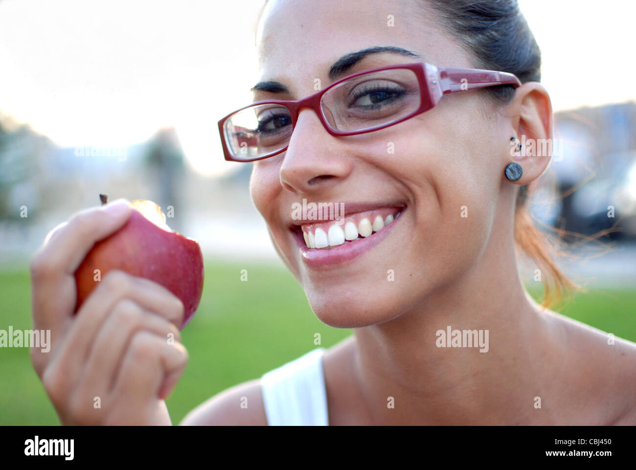 Young woman eating a red apple in nature Stock Photo - Alamy