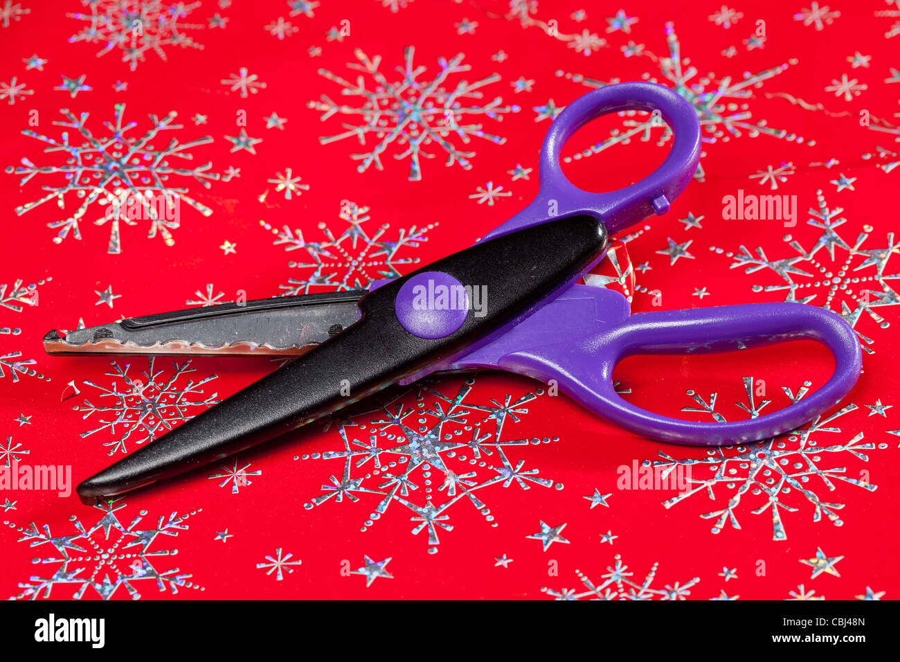 Christmas paper being cut by special scissors to create pattern in the ...
