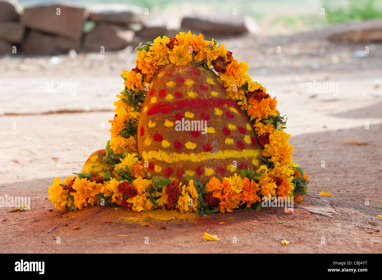 Hindu temple shrine stone surrounded with a flower garland in a rural ...