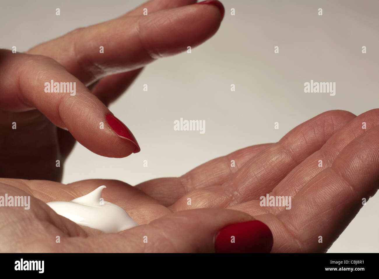 close up detail image of womans hand with red nails and a drop of hand ...