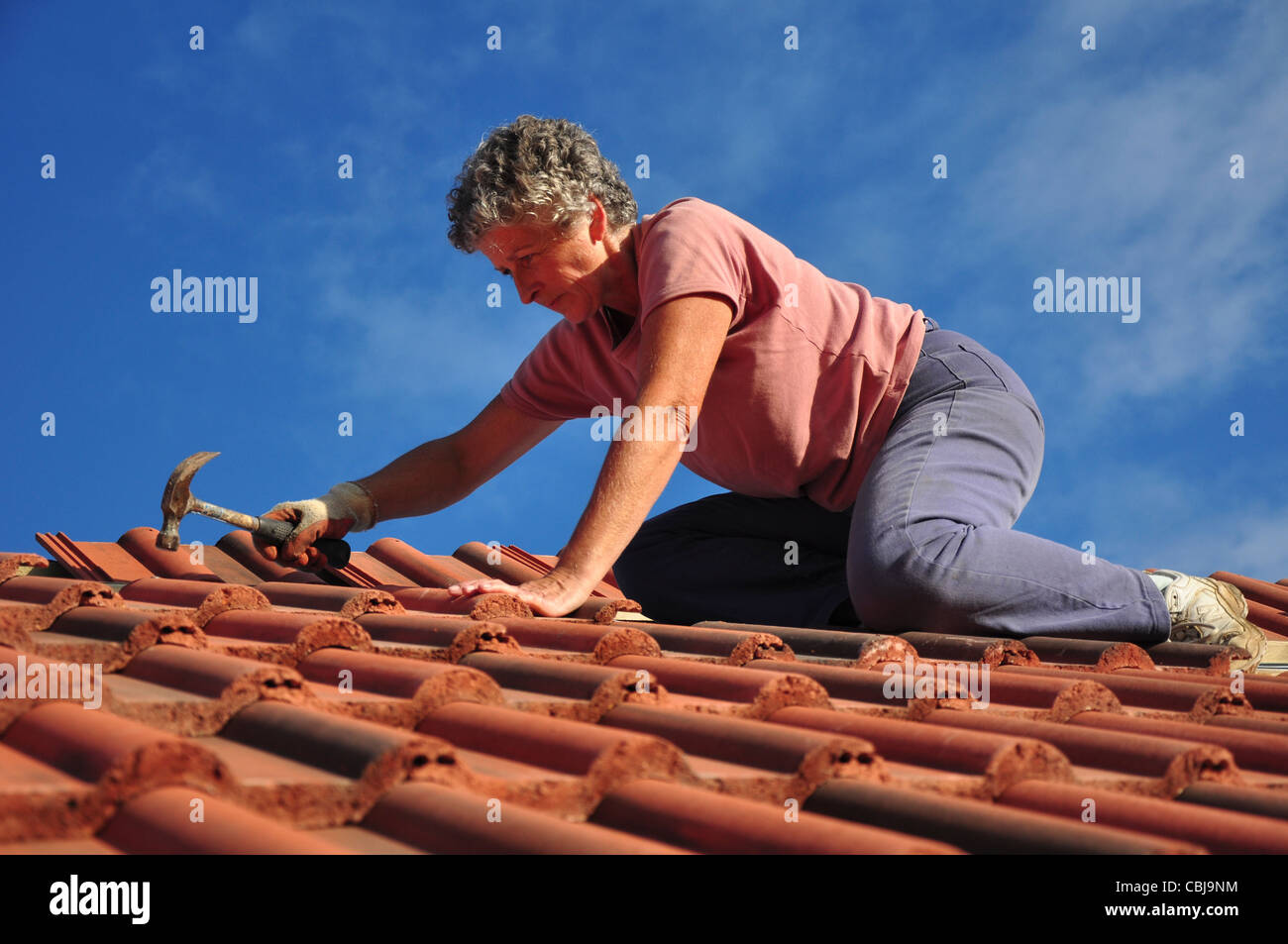 Lady fixing double roman tiles on roof Stock Photo - Alamy