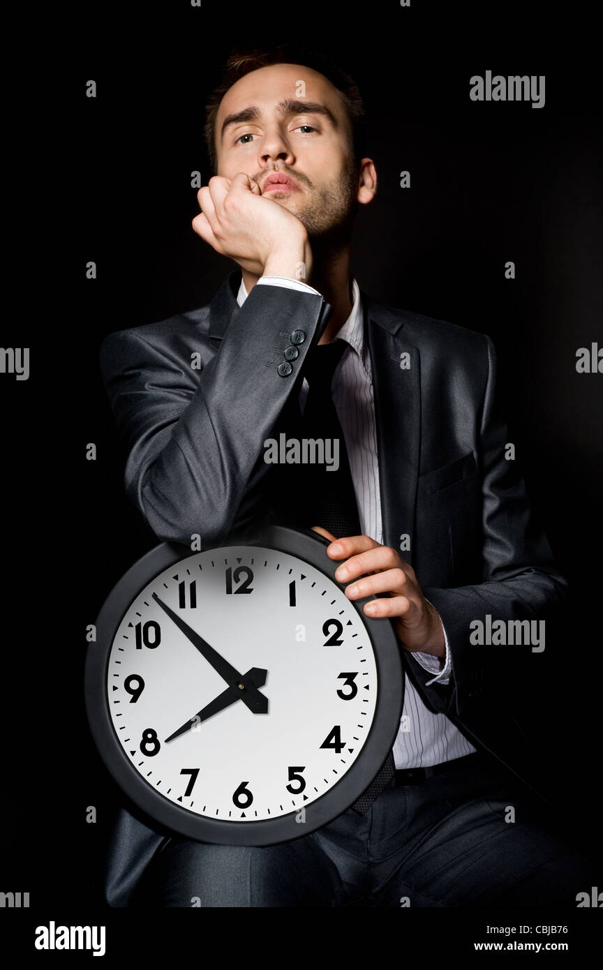 bored businessman holding clock, over black Stock Photo - Alamy