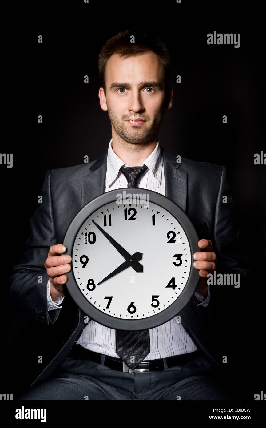 young handsome businessman holding clock, over black Stock Photo - Alamy