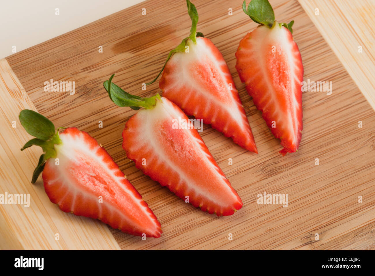 Cut fresh strawberries on cutting board Stock Photo - Alamy