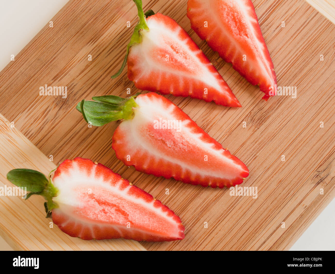 Cut fresh strawberries on cutting board Stock Photo - Alamy