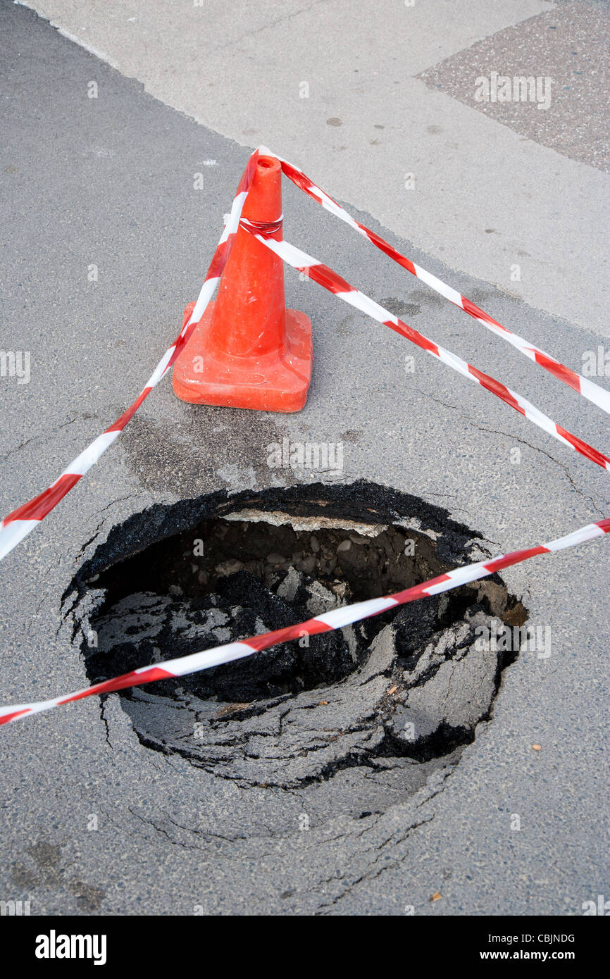 Circular hole in the road cordoned off by traffic cones and tape, Lyme ...