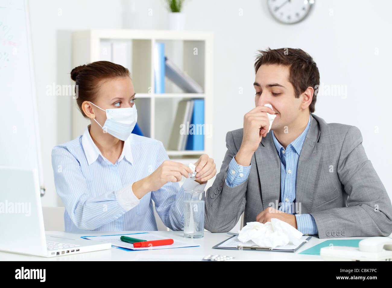 Image of sick businessman with tissue looking at his colleague in mask ...