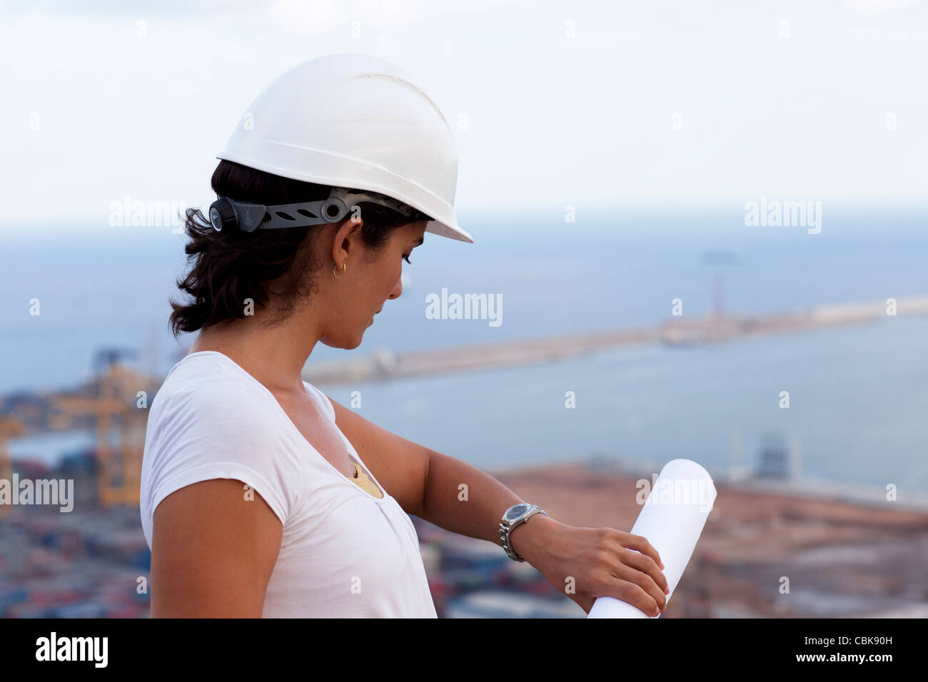 Female latin engineer with hardhat watching the clock in front of a ...