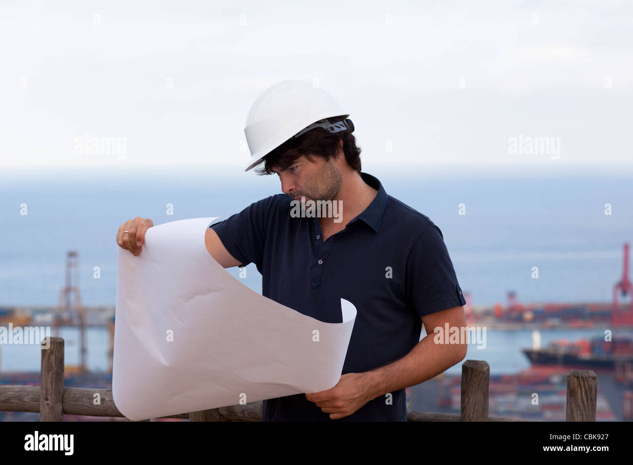Male engineer checking a plan in front of a harbour Stock Photo - Alamy