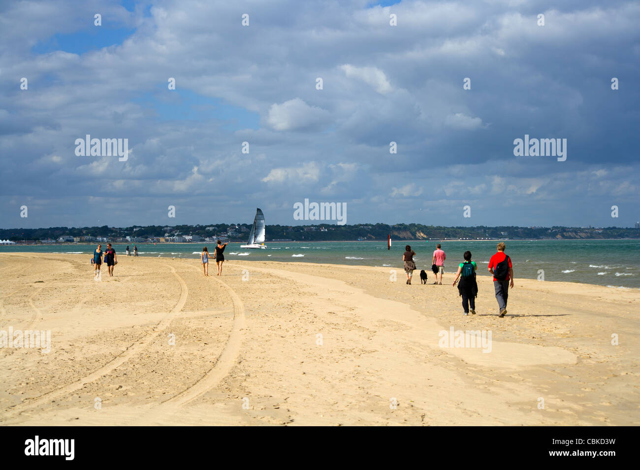 Walkers on Shell Bay beach looking towards Sandbanks, Poole, Dorset, UK ...
