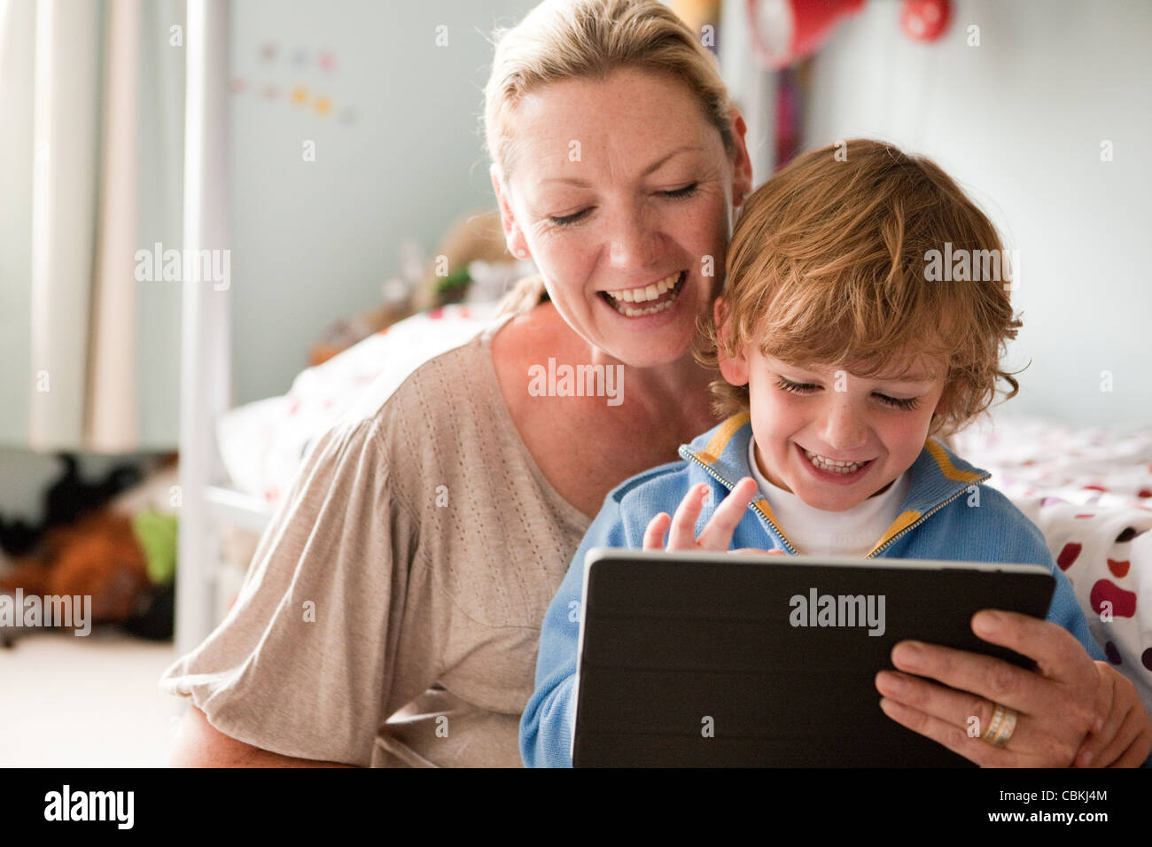 Mother using a digital tablet with her son Stock Photo - Alamy