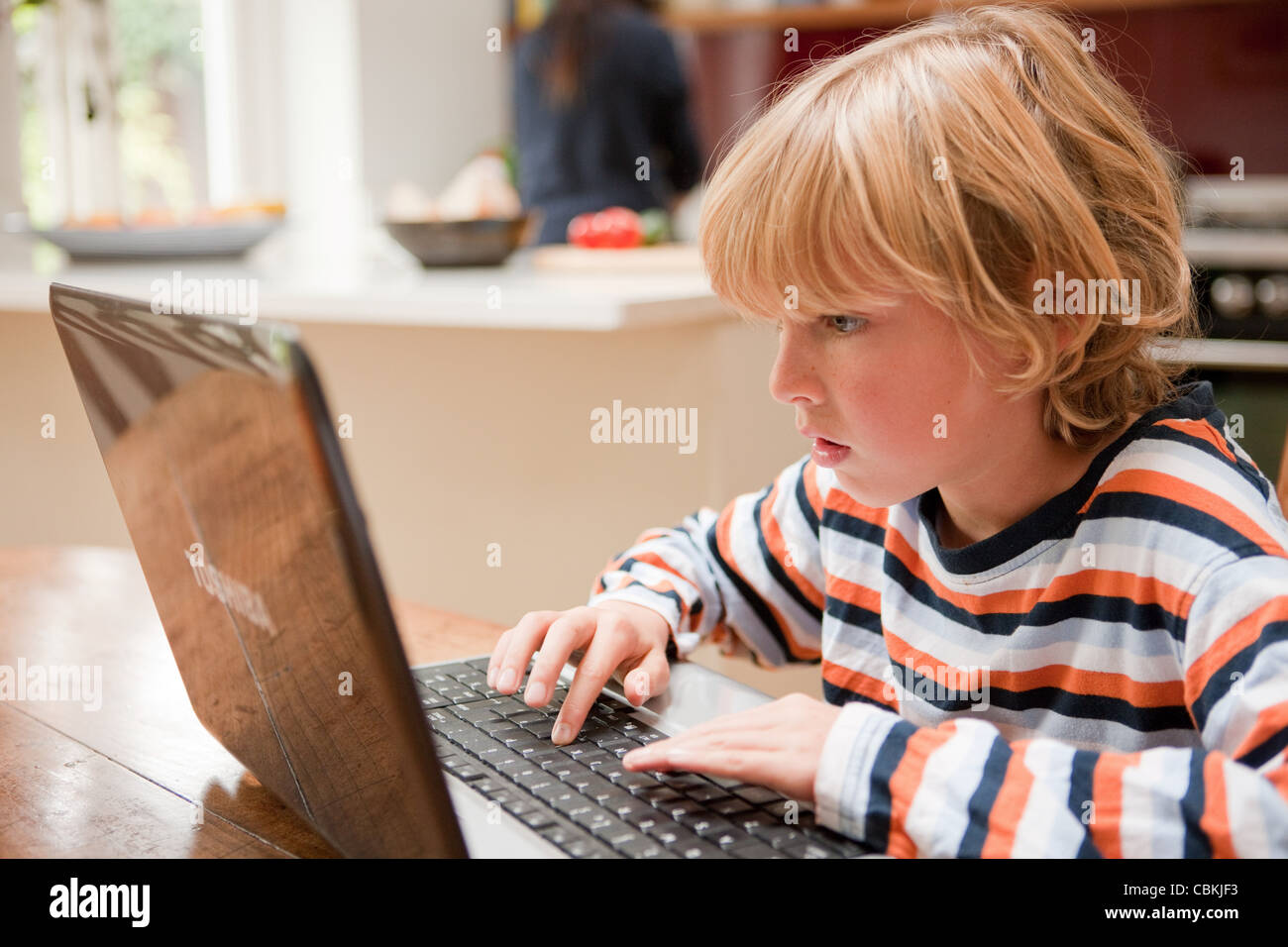 Young boy looking at a laptop monitor while typing Stock Photo - Alamy