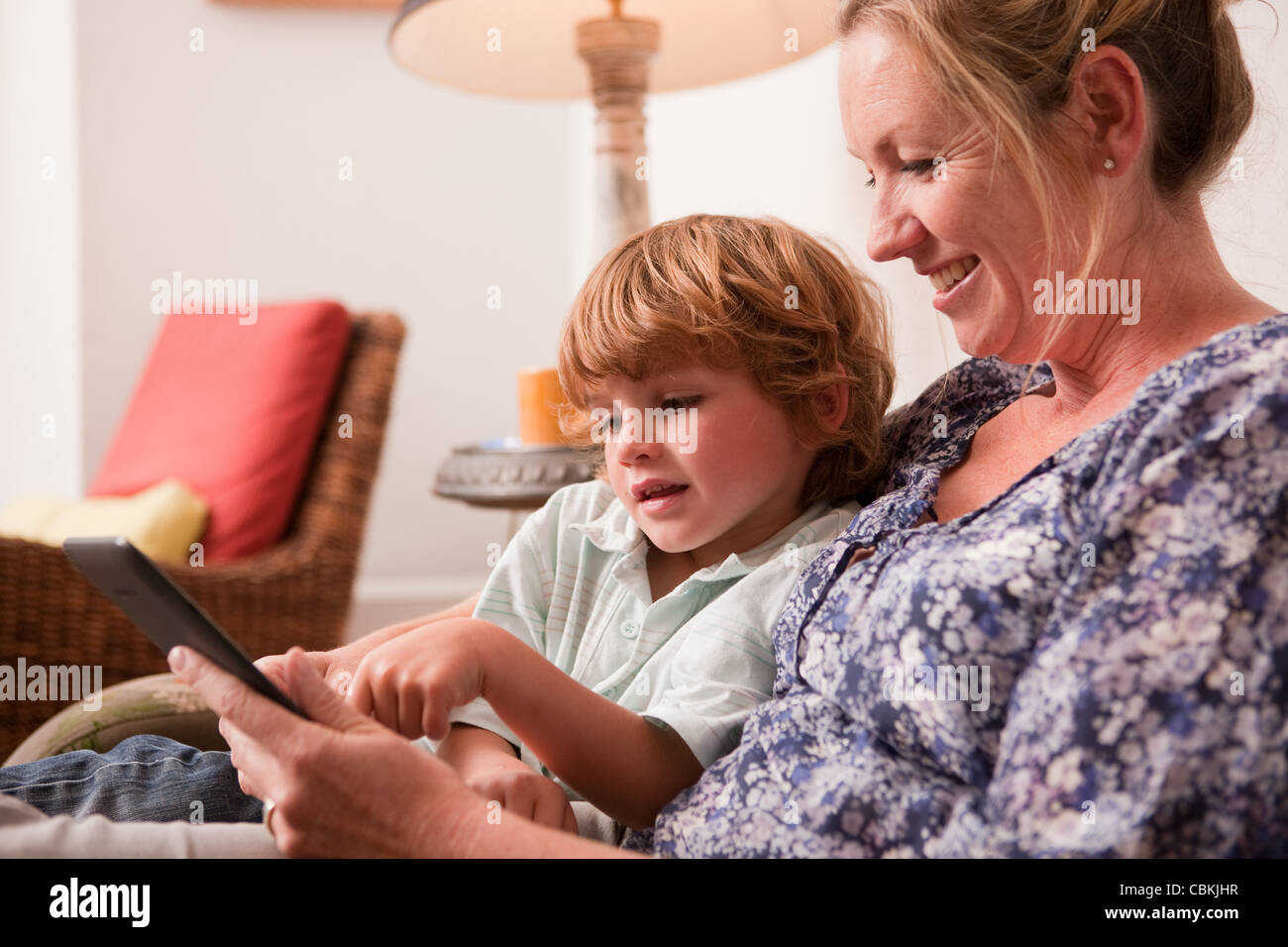 Son using a digital tablet with his mother Stock Photo - Alamy