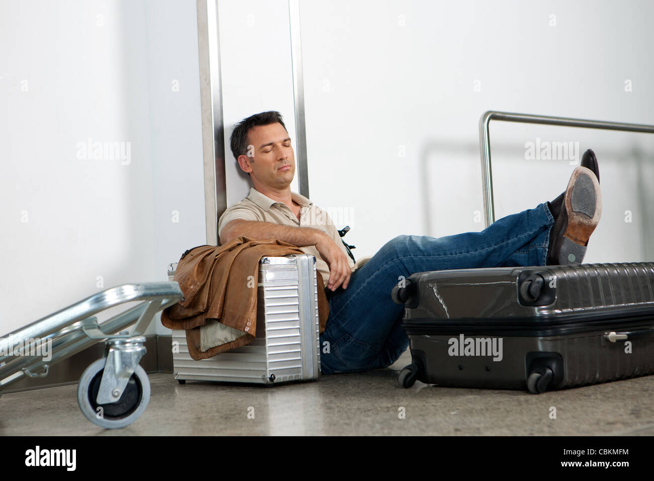 Man sleeping on luggage in airport Stock Photo - Alamy