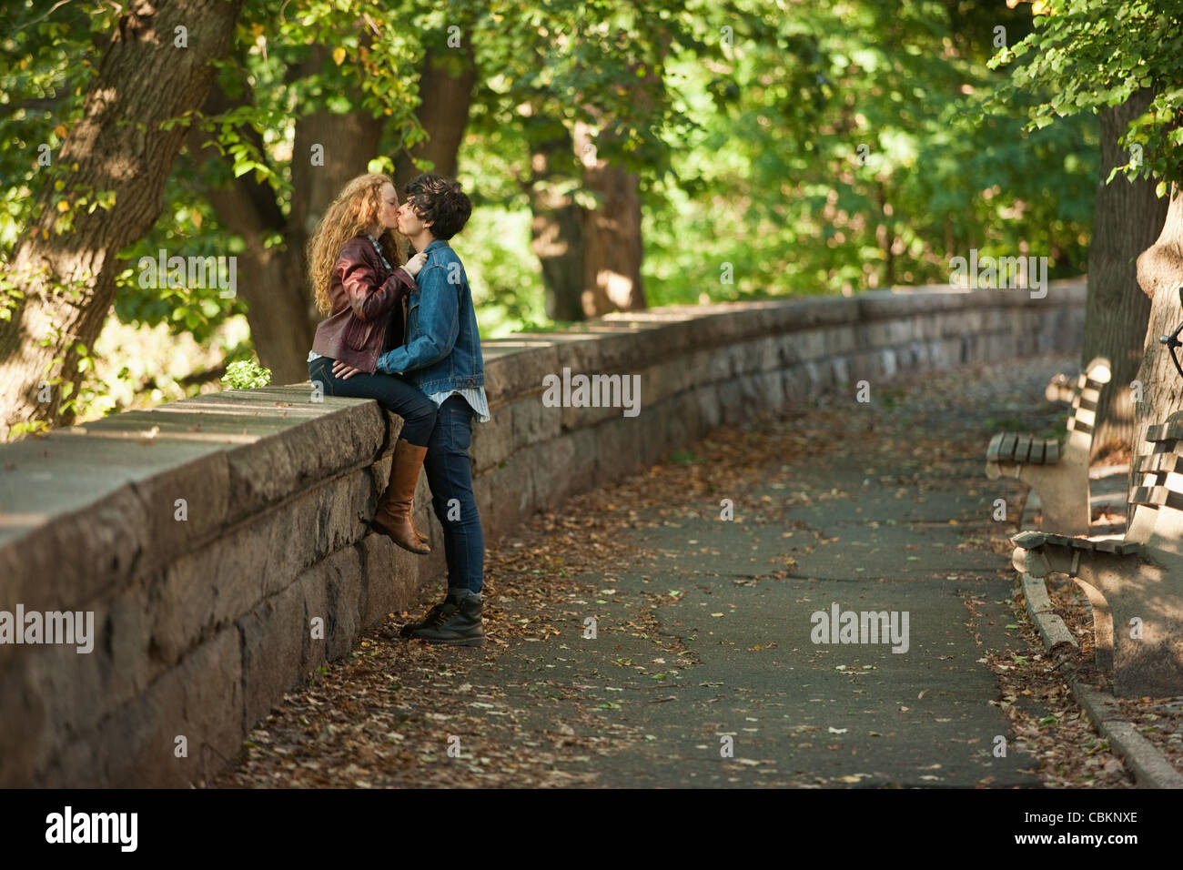 Young couple embracing on wall in park Stock Photo - Alamy