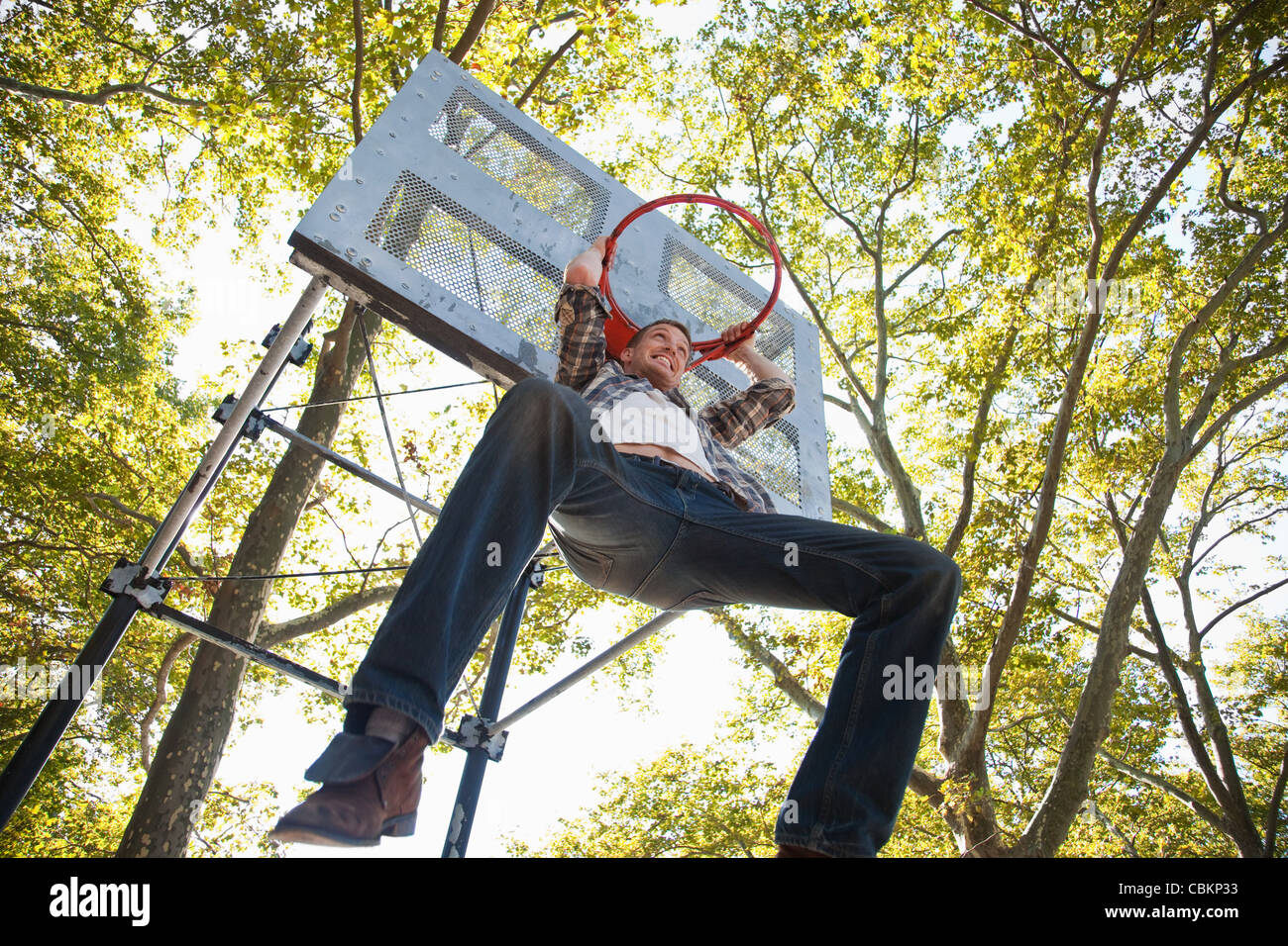 Mid adult man hanging from basketball hoop Stock Photo - Alamy