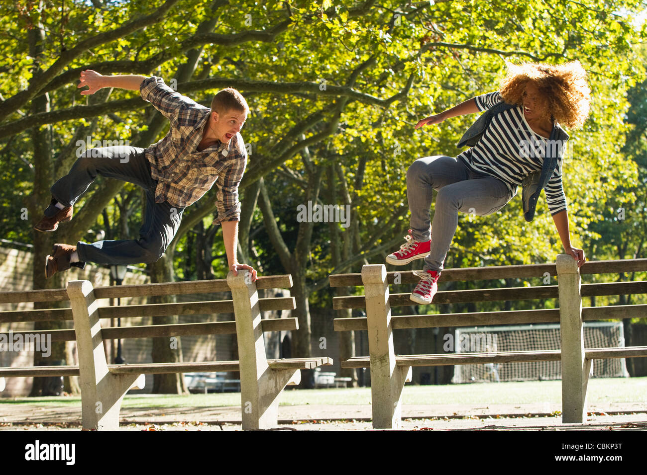 Couple leaping over park benches Stock Photo - Alamy