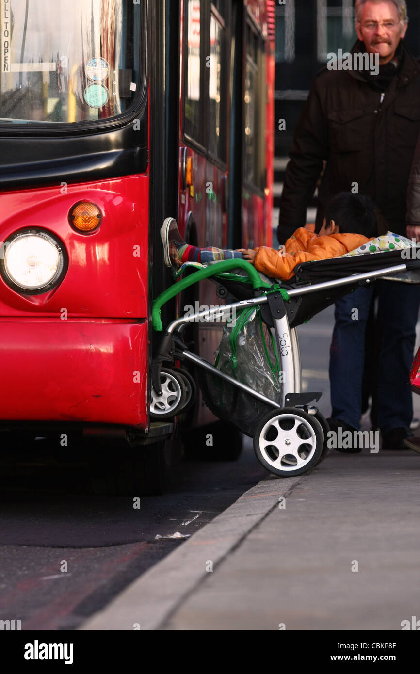 a pushchair carrying a baby being loaded onto a red London bus Stock ...