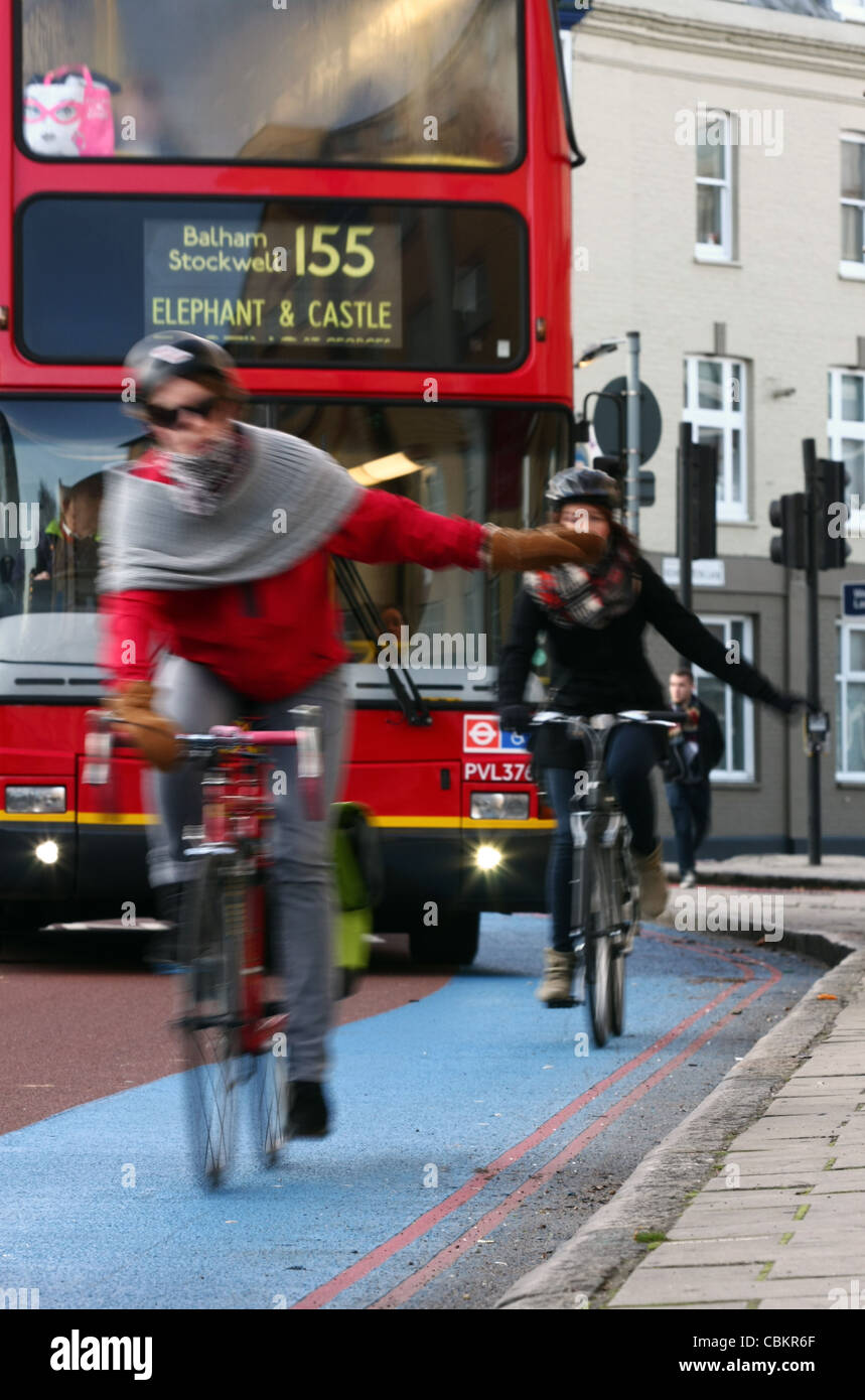 two cyclists signaling to turn left while traveling along a cycle ...