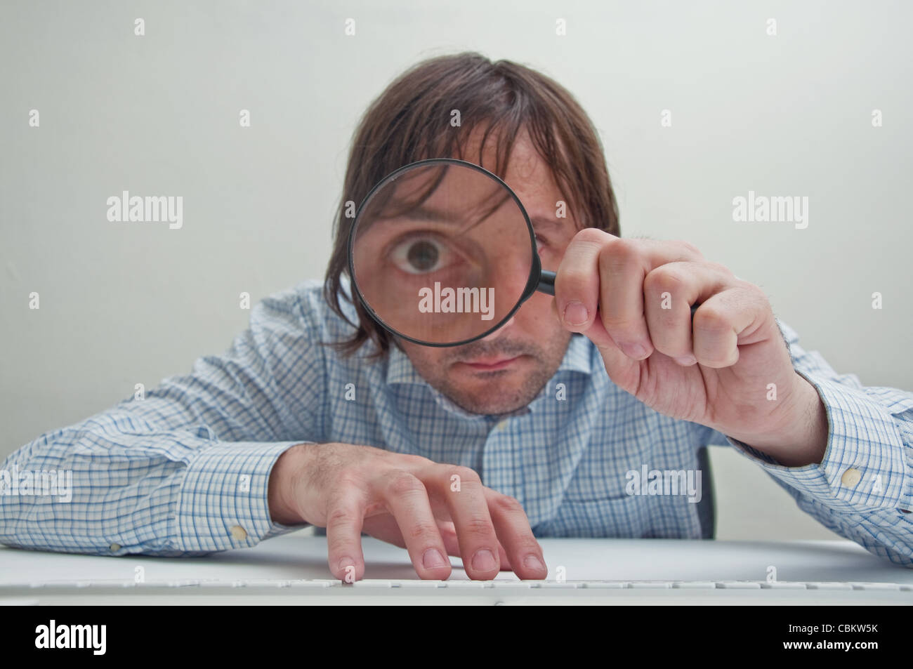 Funny image of a business person with a magnifying glass, one eye is ...