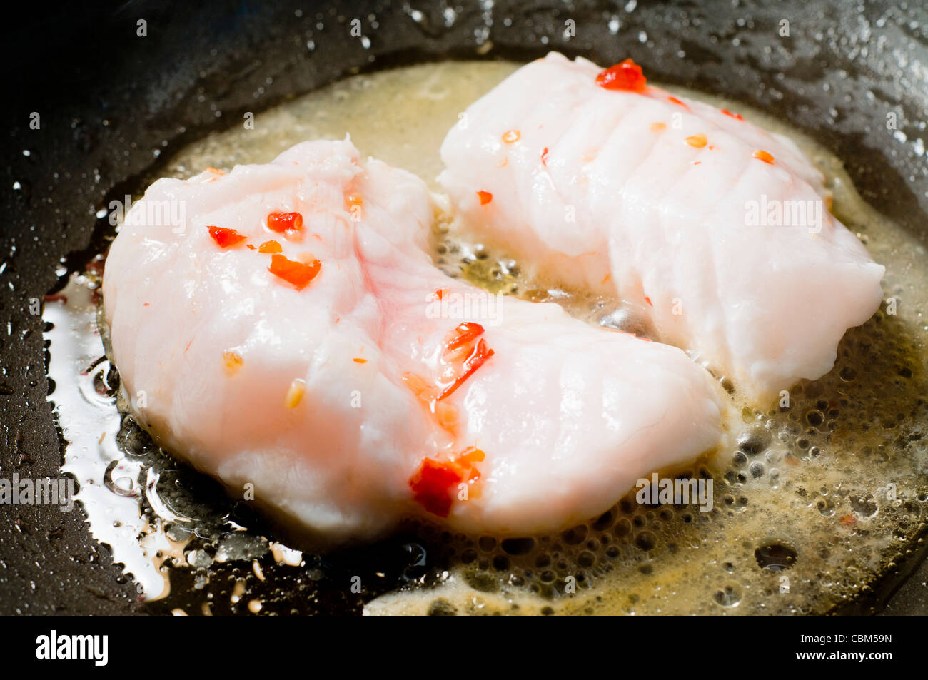 monkfish cooking in wok in oil with chopped chillie Stock Photo - Alamy