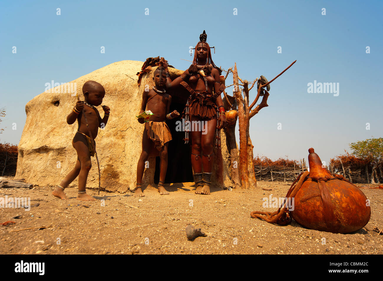 Himba woman with kids in front of his mud hut in a village near Epupa ...