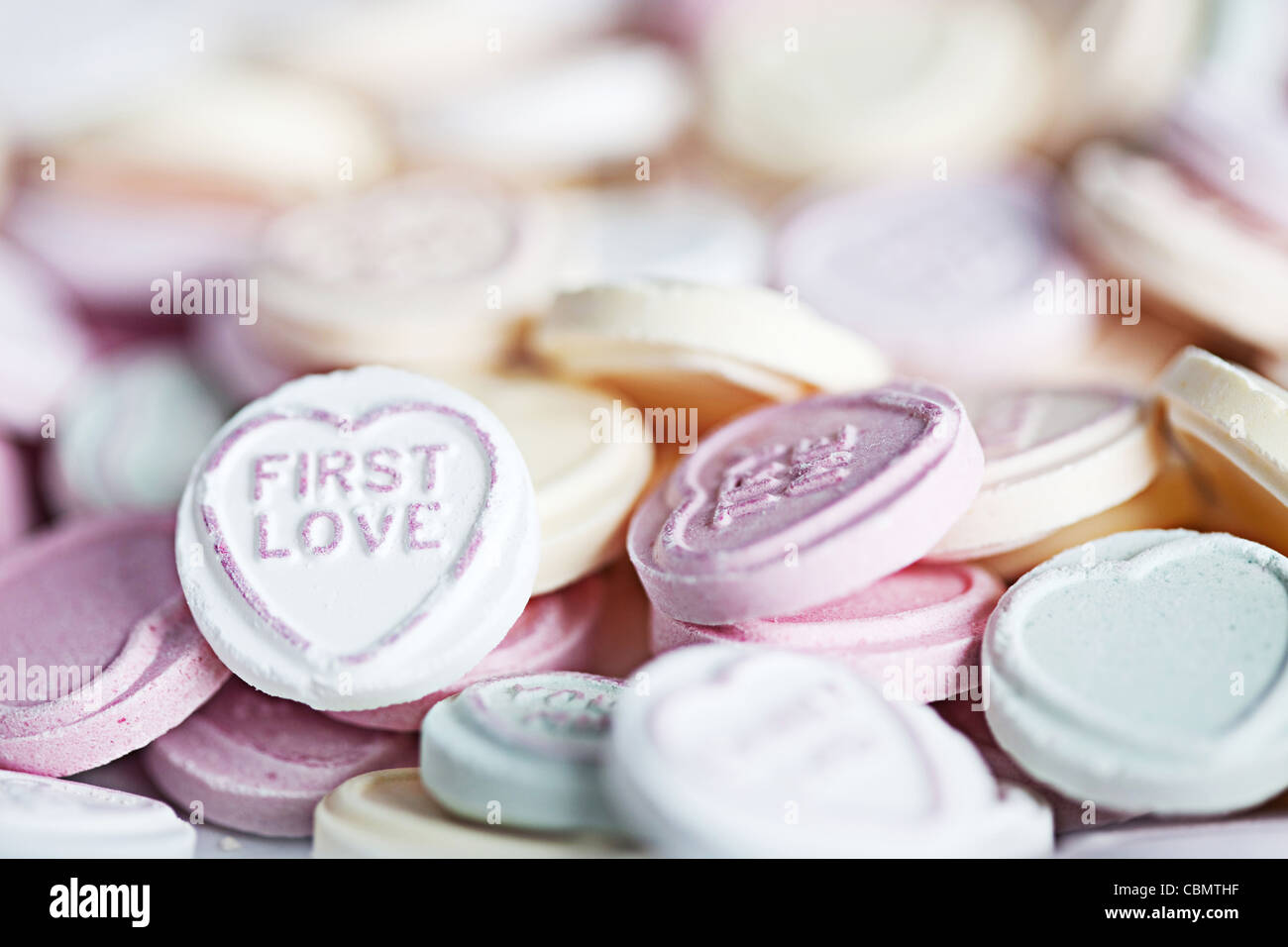 A close crop of a bowl of love heart sweets, focusing on the "first ...