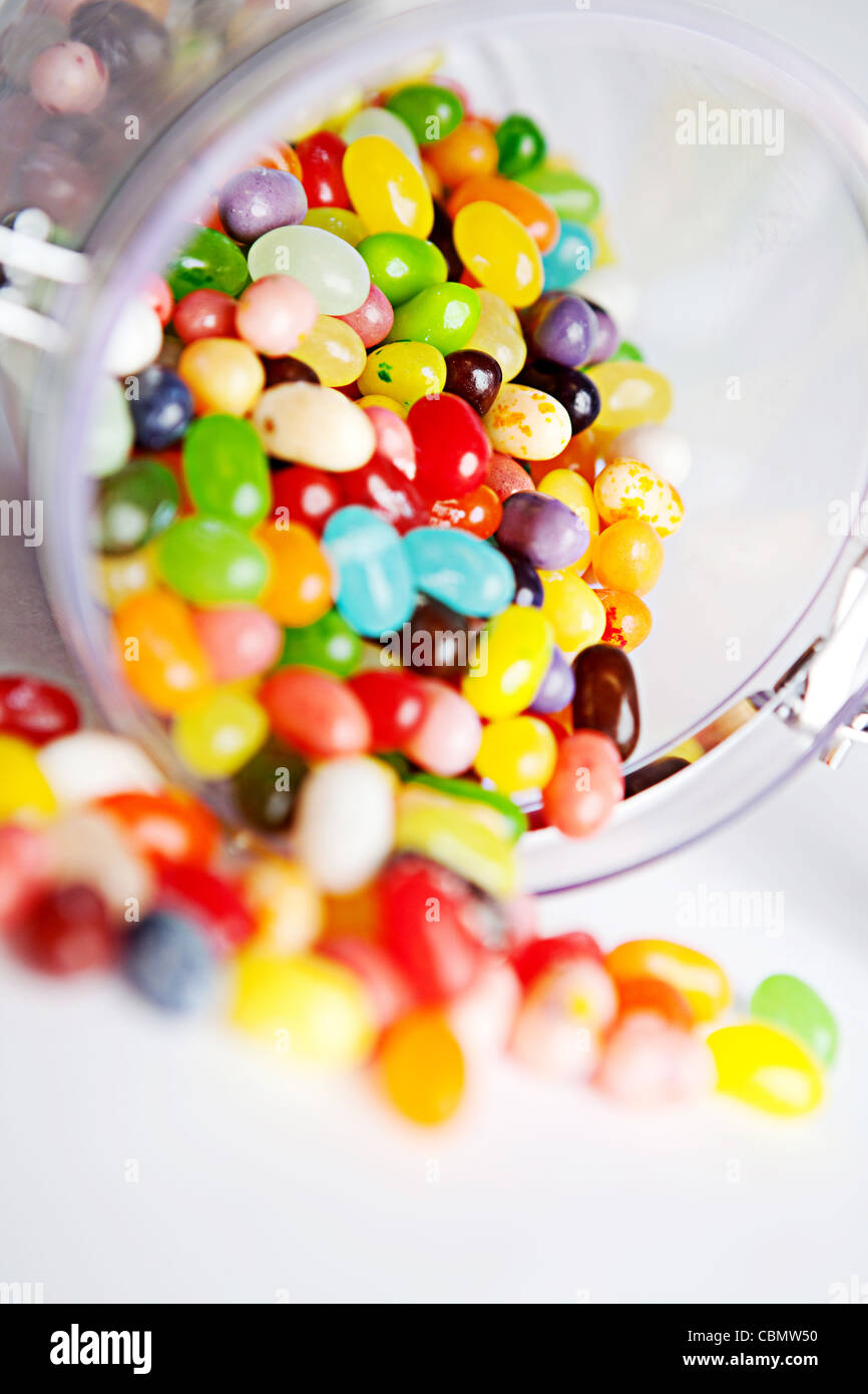 Colourful jelly bean sweets spilling out of a glass jar Stock Photo - Alamy